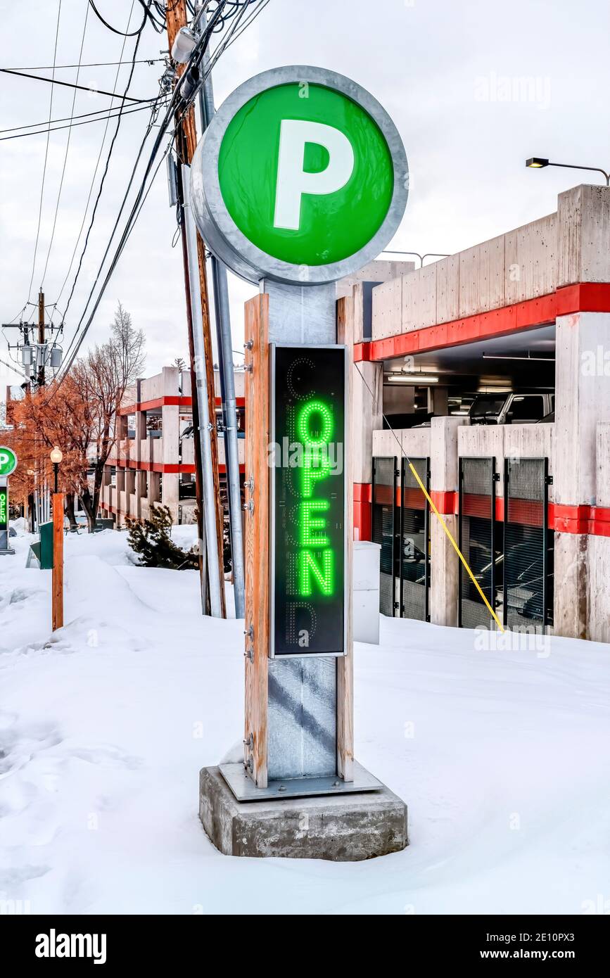Modern electronic parking sign on snowy landscape outside commercial ...