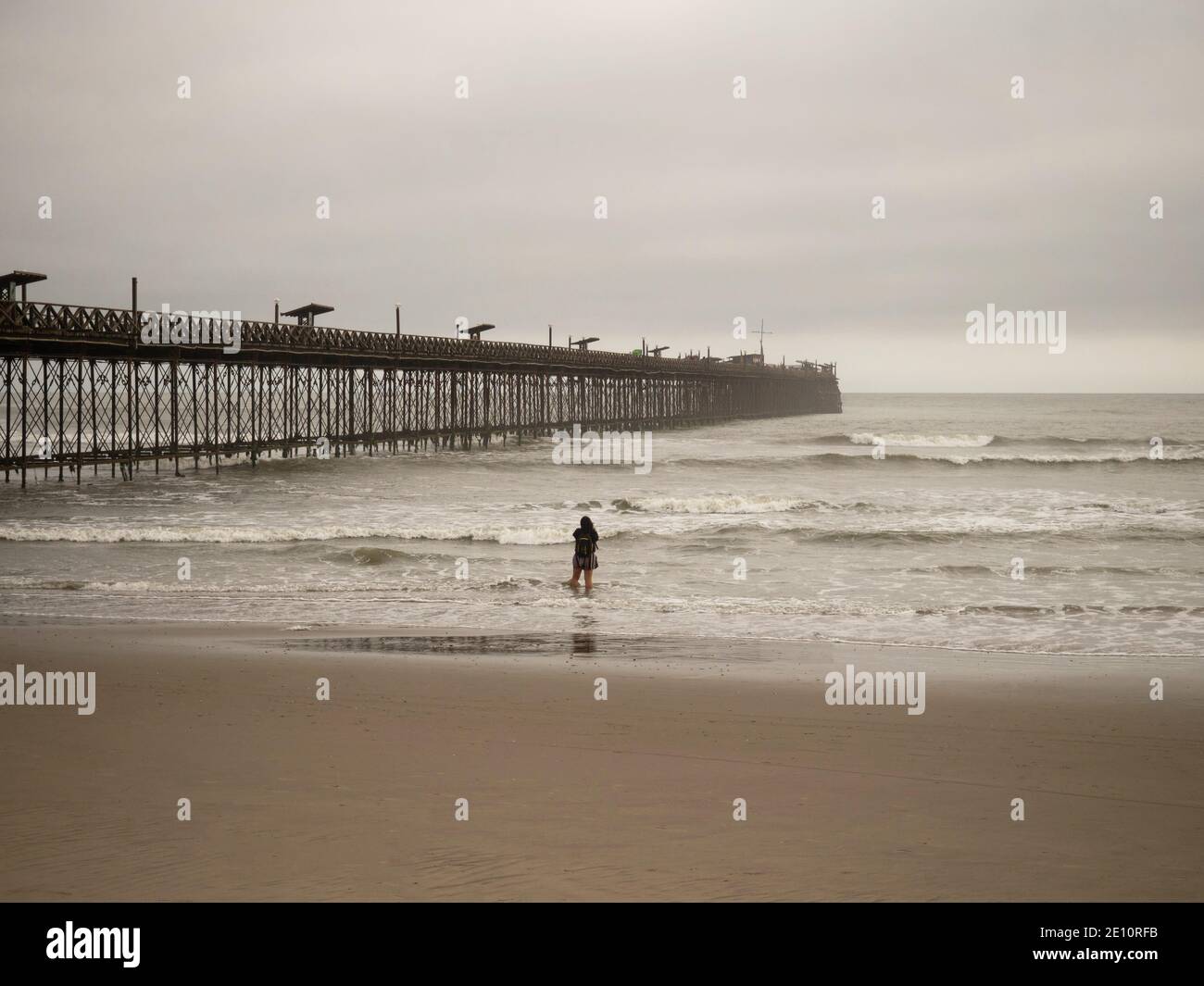 Girl standing at Playa Pimentel surfer town sand beach with Muelle pier ...
