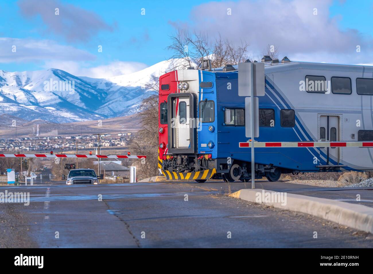 Train on railway and road intersection against snowy mountain and blue ...