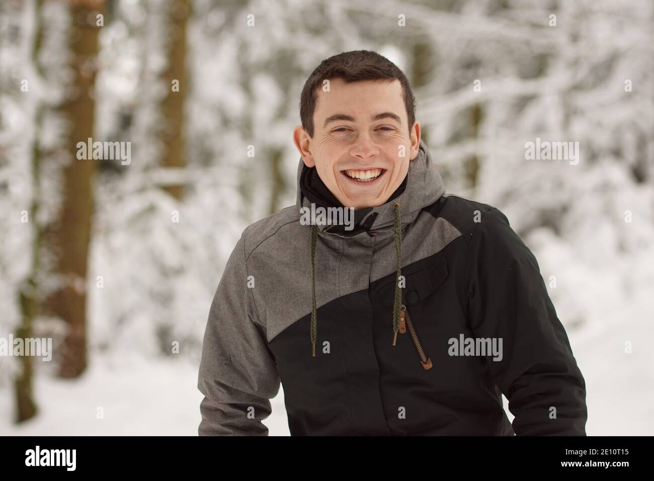 Winter - happy young man having fun in snow and laughing, smiling into ...