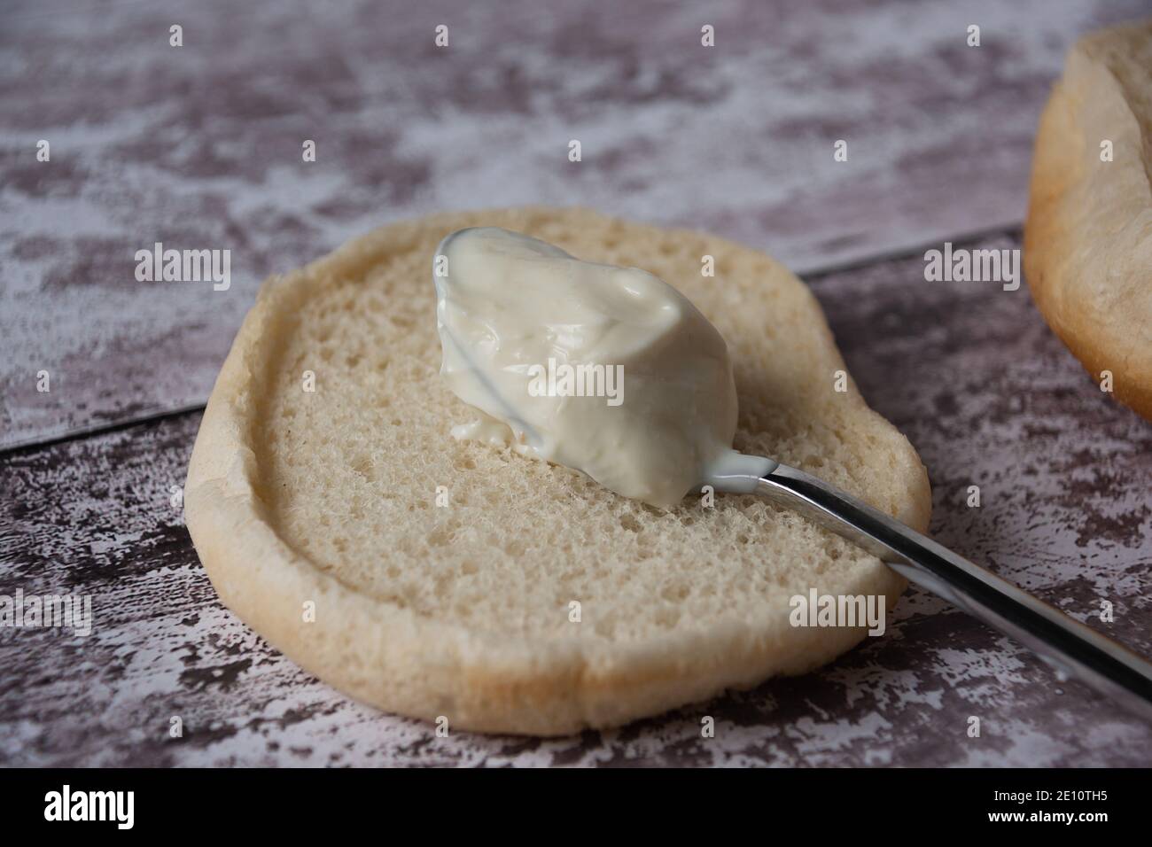 A white burger bun base viewed from the side about to be covered with ...