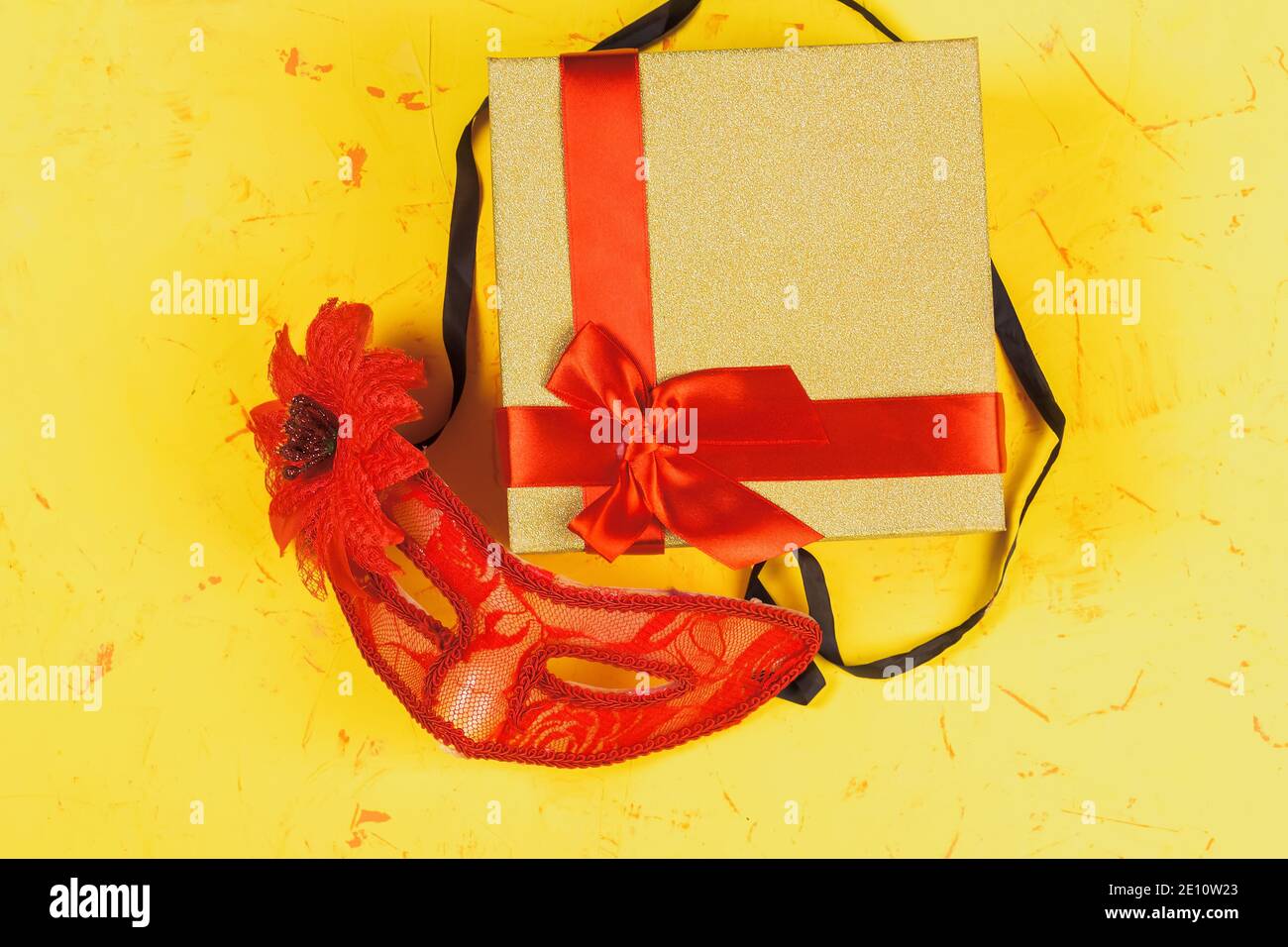 Colored square gift box on concrete background and red carnival mask ...