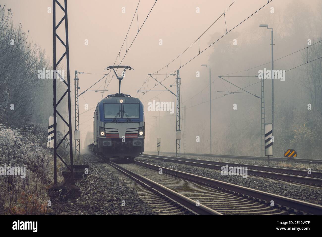 Modern electric locomotive in the fog. Freight train at winter ...