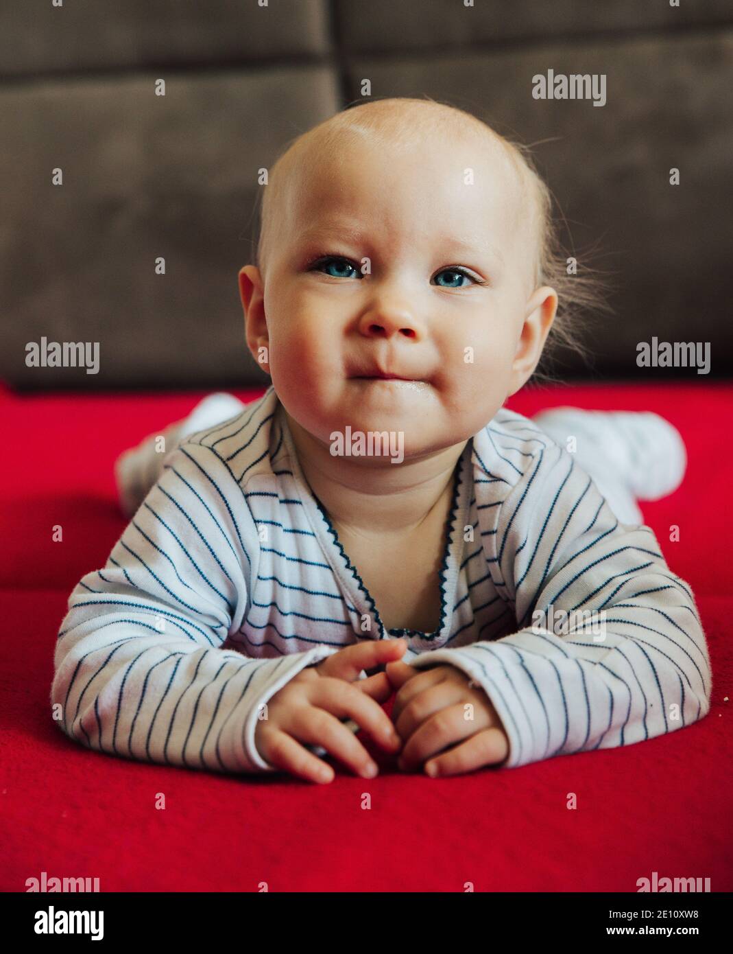 curious baby girl lying on bed, smiling front view Stock Photo - Alamy