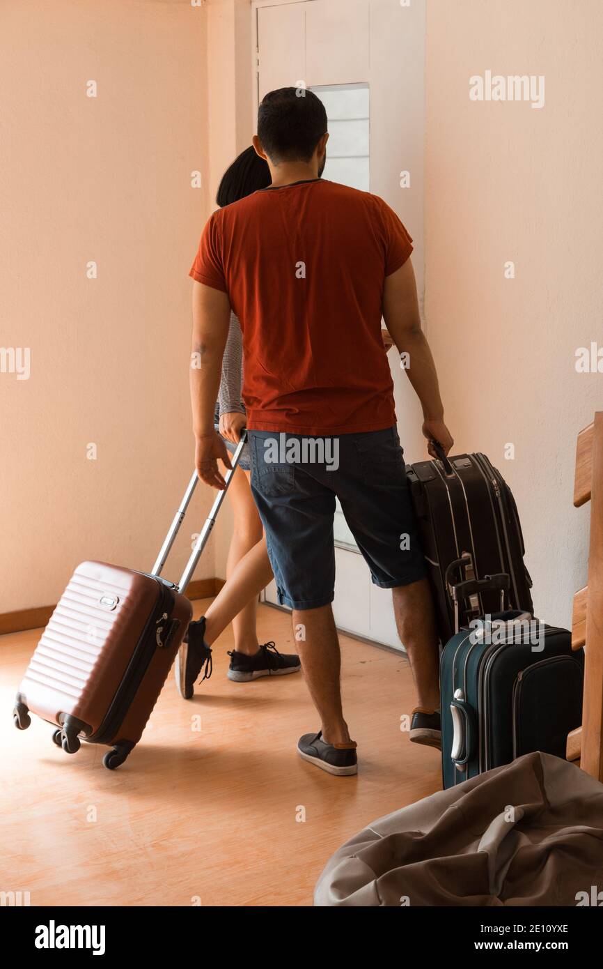two people leaving their home for a trip with suitcases in their living ...