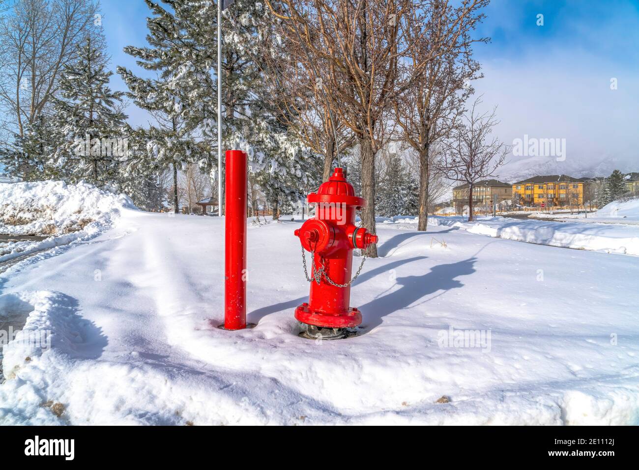 Vibrant red fire hydrant and pole against nature landcsape of snow in ...