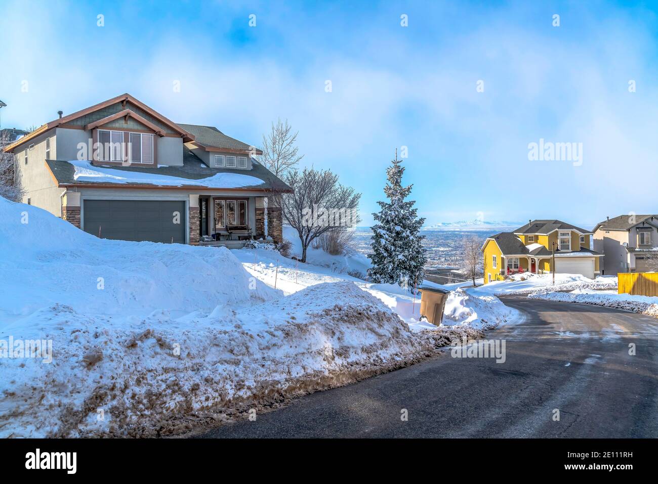 Snowy neighborhood with homes and road overlooking valley and mountain ...