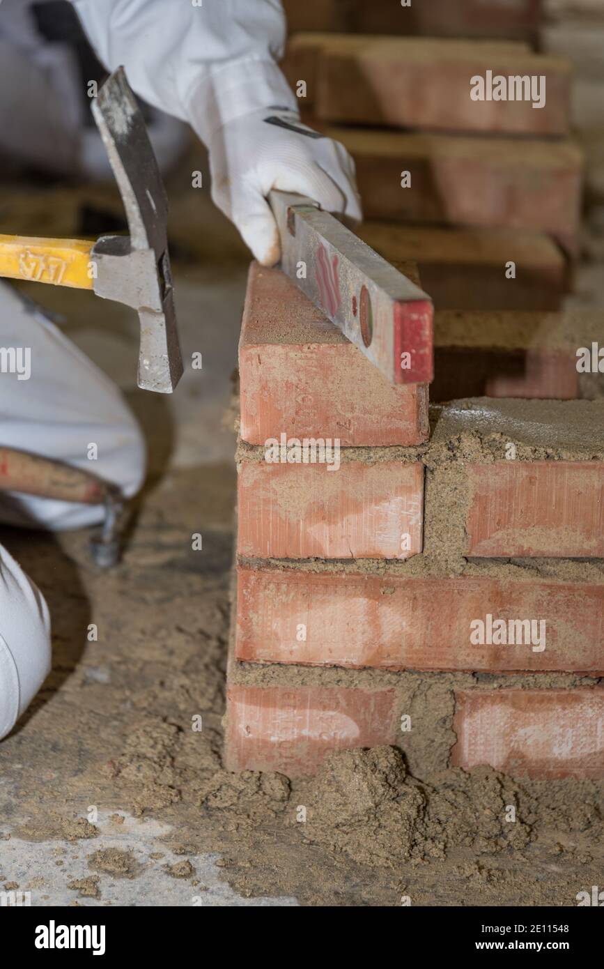 Bricklayer Builds Brick Wall With Spirit Level And Masonry Hammer Stock ...