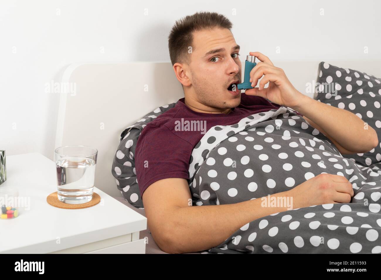 Young male patient with seasonal influenza is using an inhaler with ...