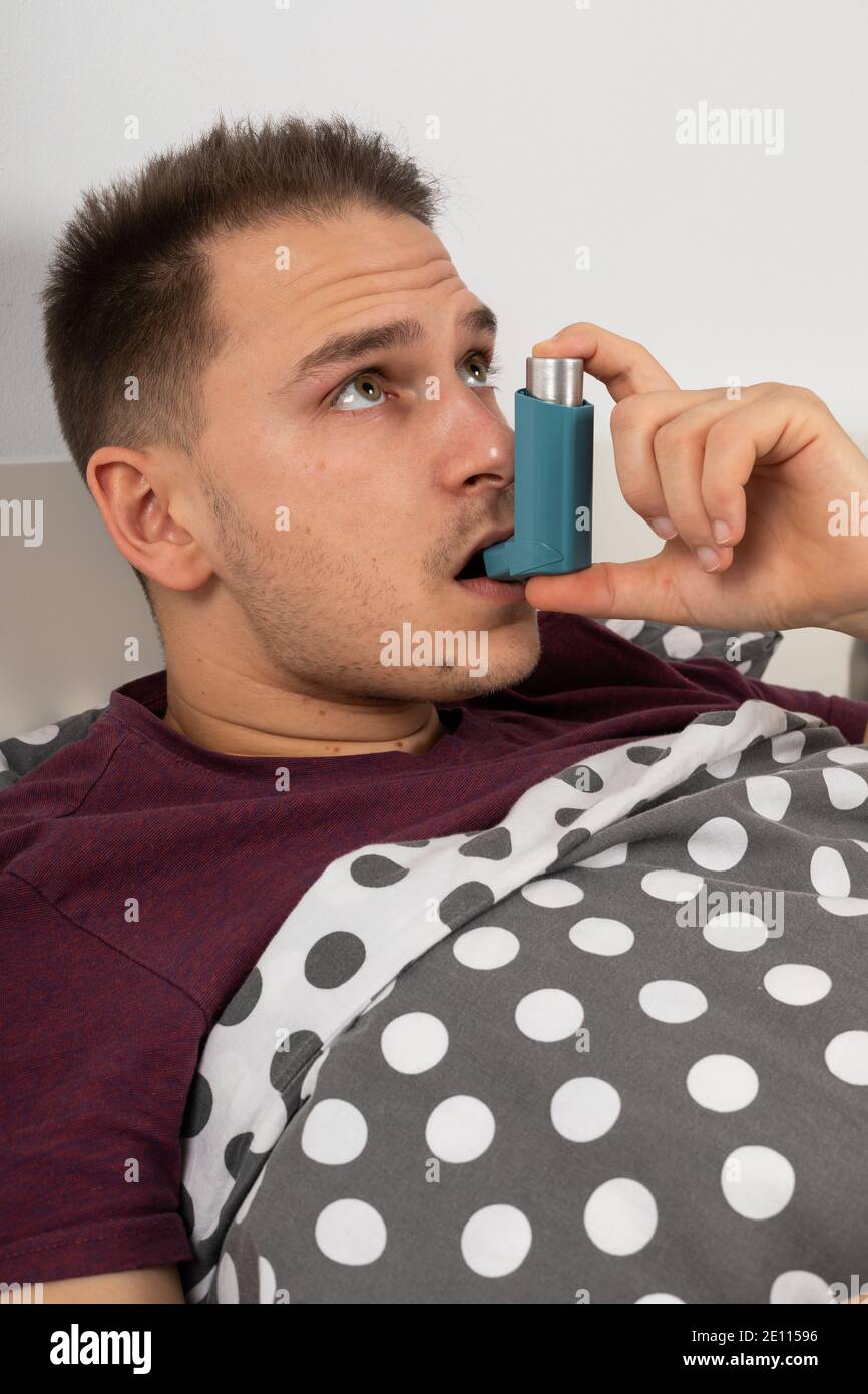 Young male patient with seasonal influenza is using an inhaler with ...