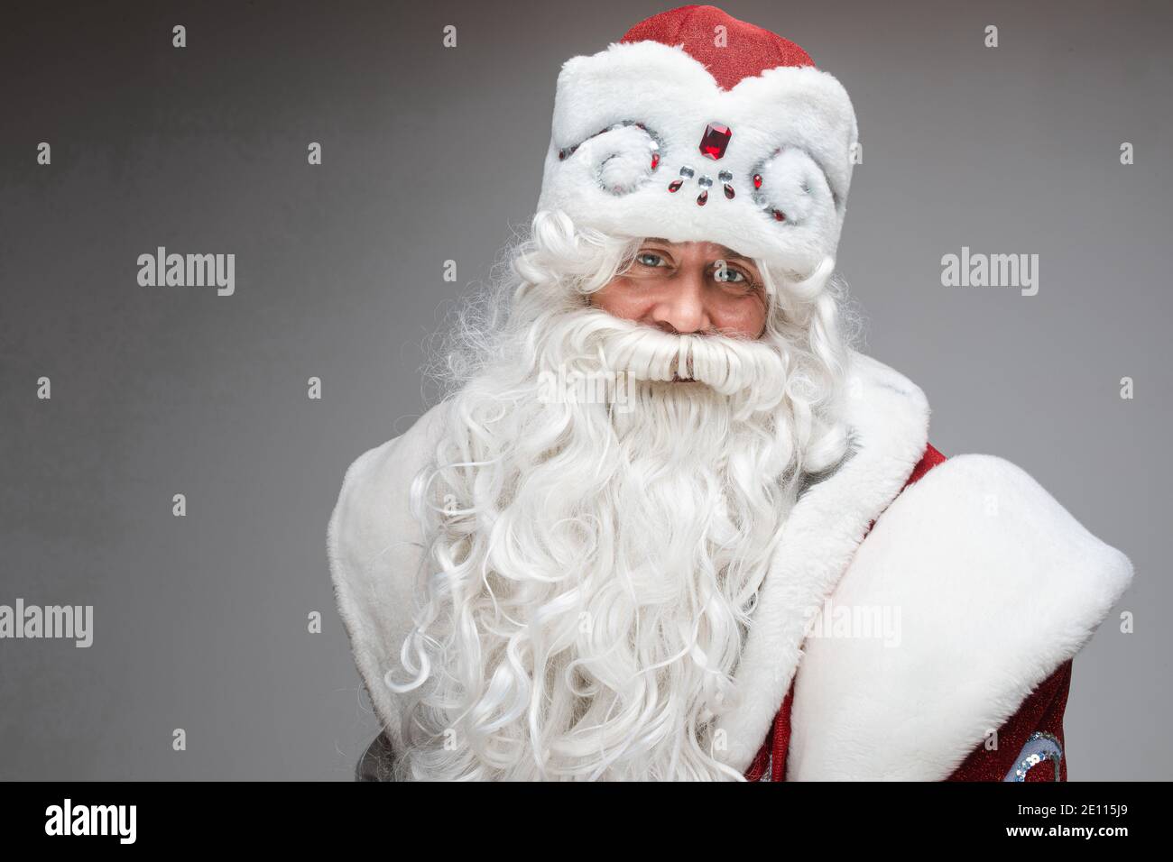 Happy friendly Santa Claus posing on gray studio background with copy ...