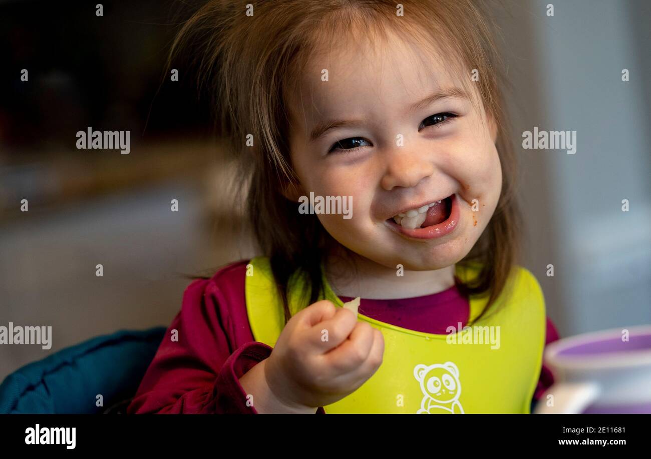Sweet young child smiles at the table with a slice of pear Stock Photo ...