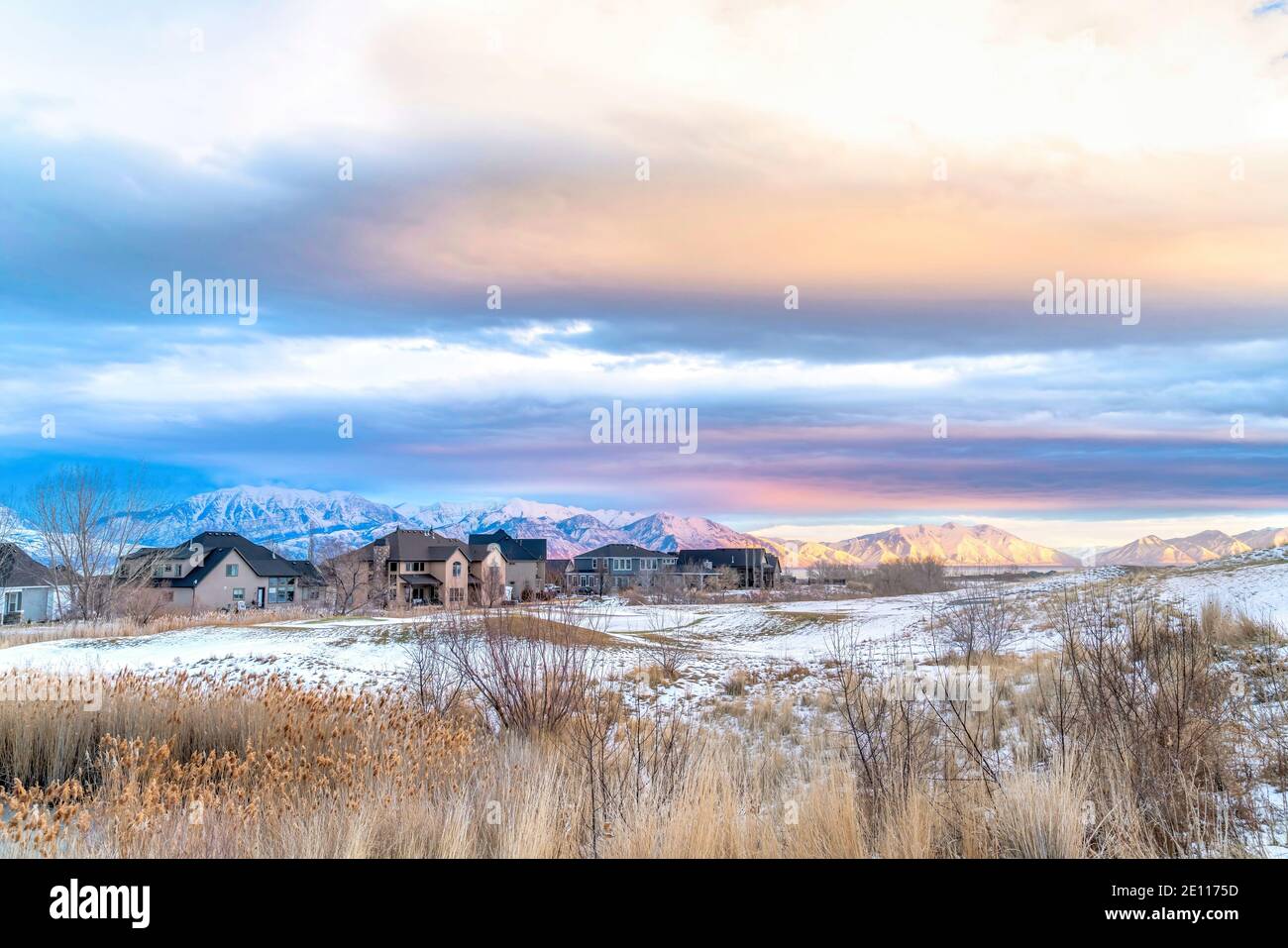 Sunset view of snowy valley in winter with homes against sunlit frosted ...