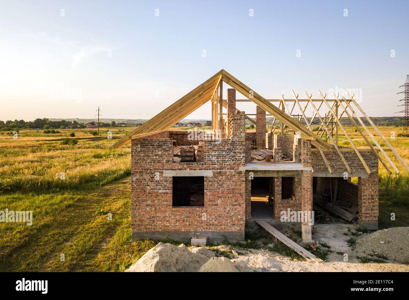 Unfinished brick house with wooden roof structure under construction ...