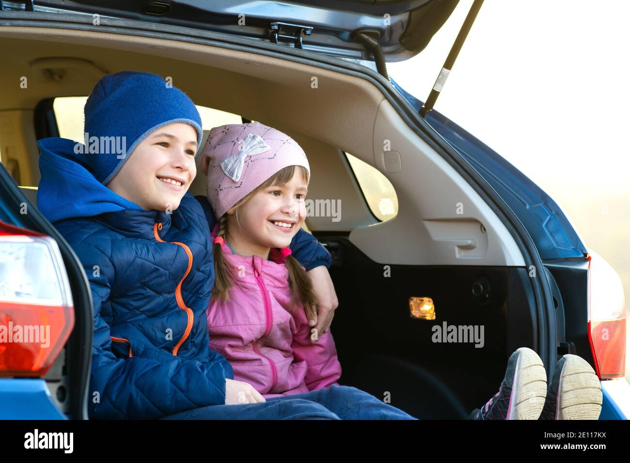 Two happy children boy and girl sitting together in a car trunk ...