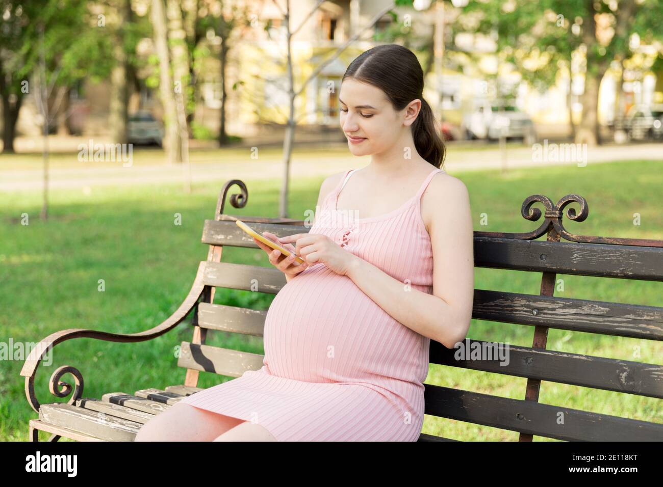 pregnant woman sits on a park bench and texting on phone Stock Photo ...
