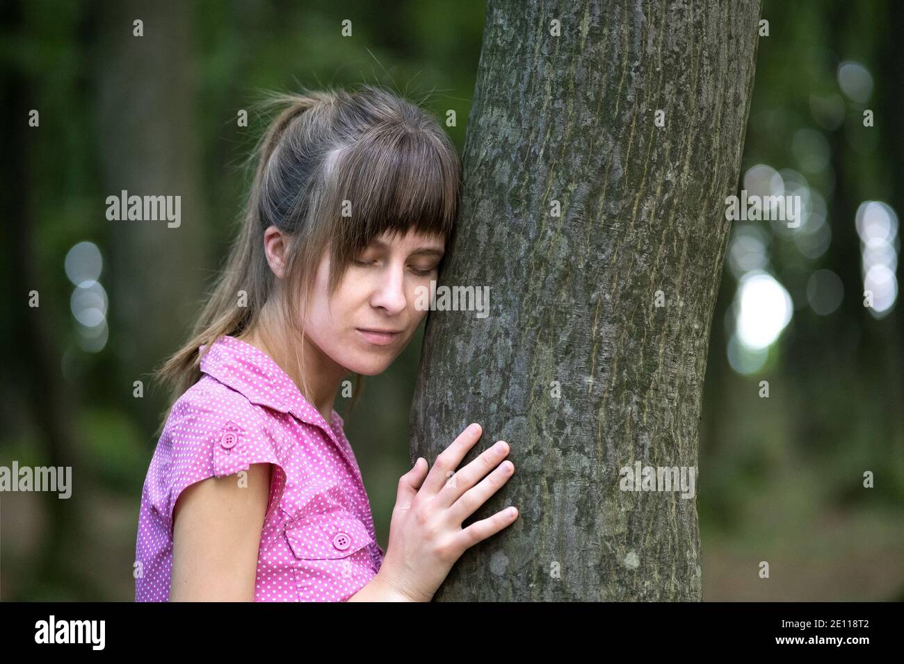 Young woman leaning to tree trunk in summer forest Stock Photo - Alamy