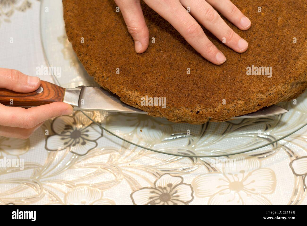 Closeup of female hand holding sharp knife cutting biscuit chocolate ...
