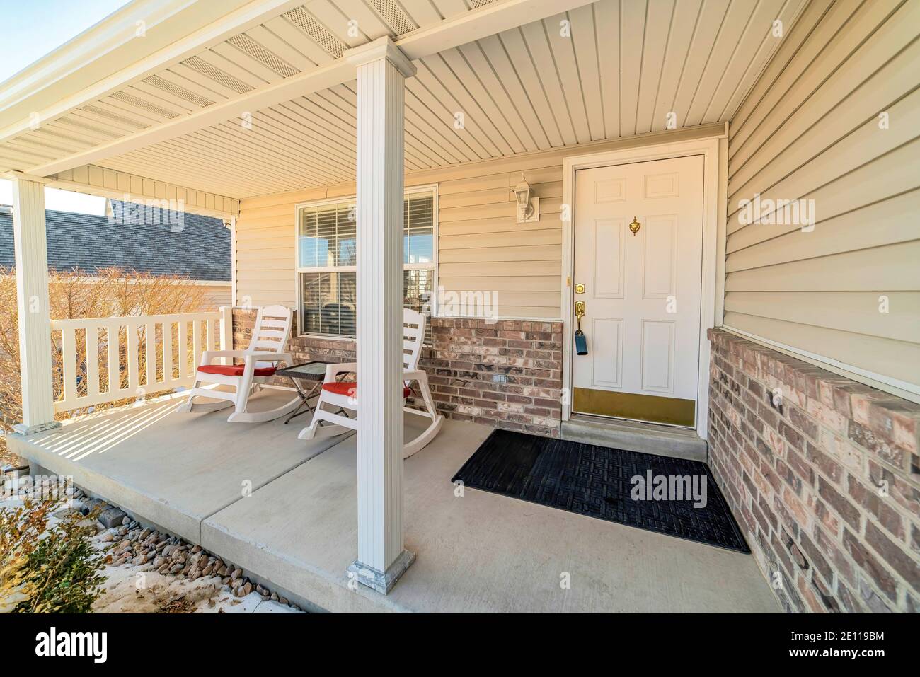 Open front porch with rocking chairs against white siding and stone ...
