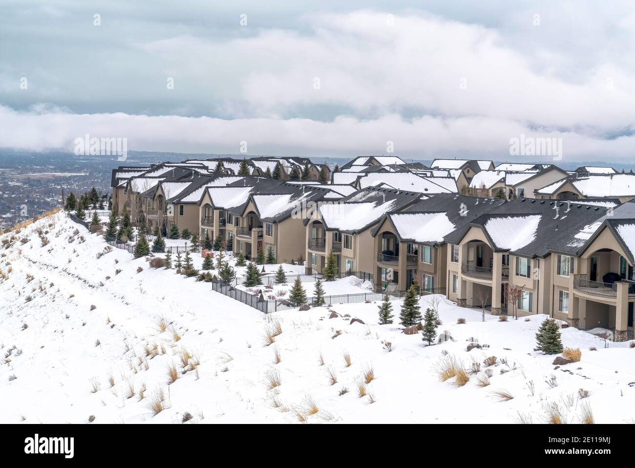 Identical homes with balconies and gray roofs on snow covered terrain ...