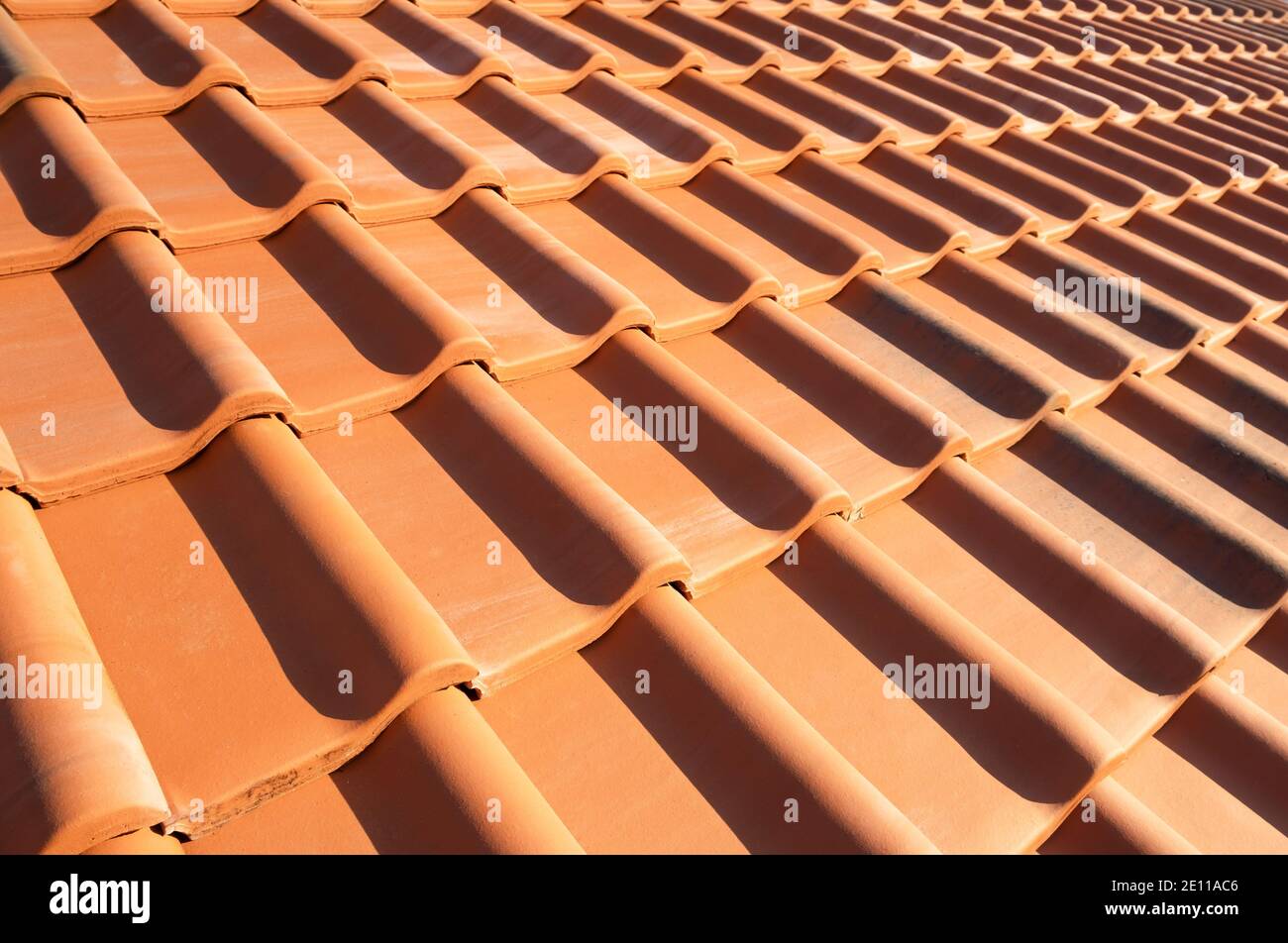 Overlapping rows of yellow ceramic roofing tiles covering residential ...
