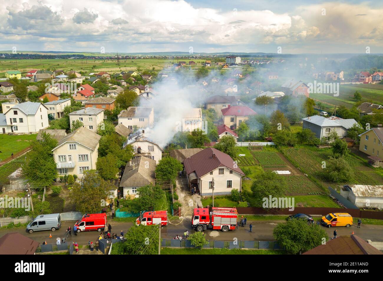 Aerial view of a house on fire with orange flames and white thick smoke ...