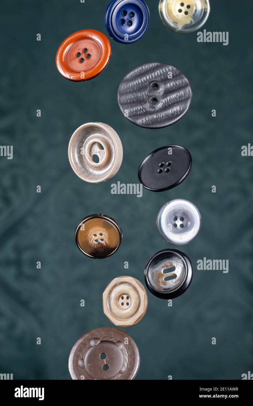 Colored vintage clothes buttons levitating on a green textured fabric ...
