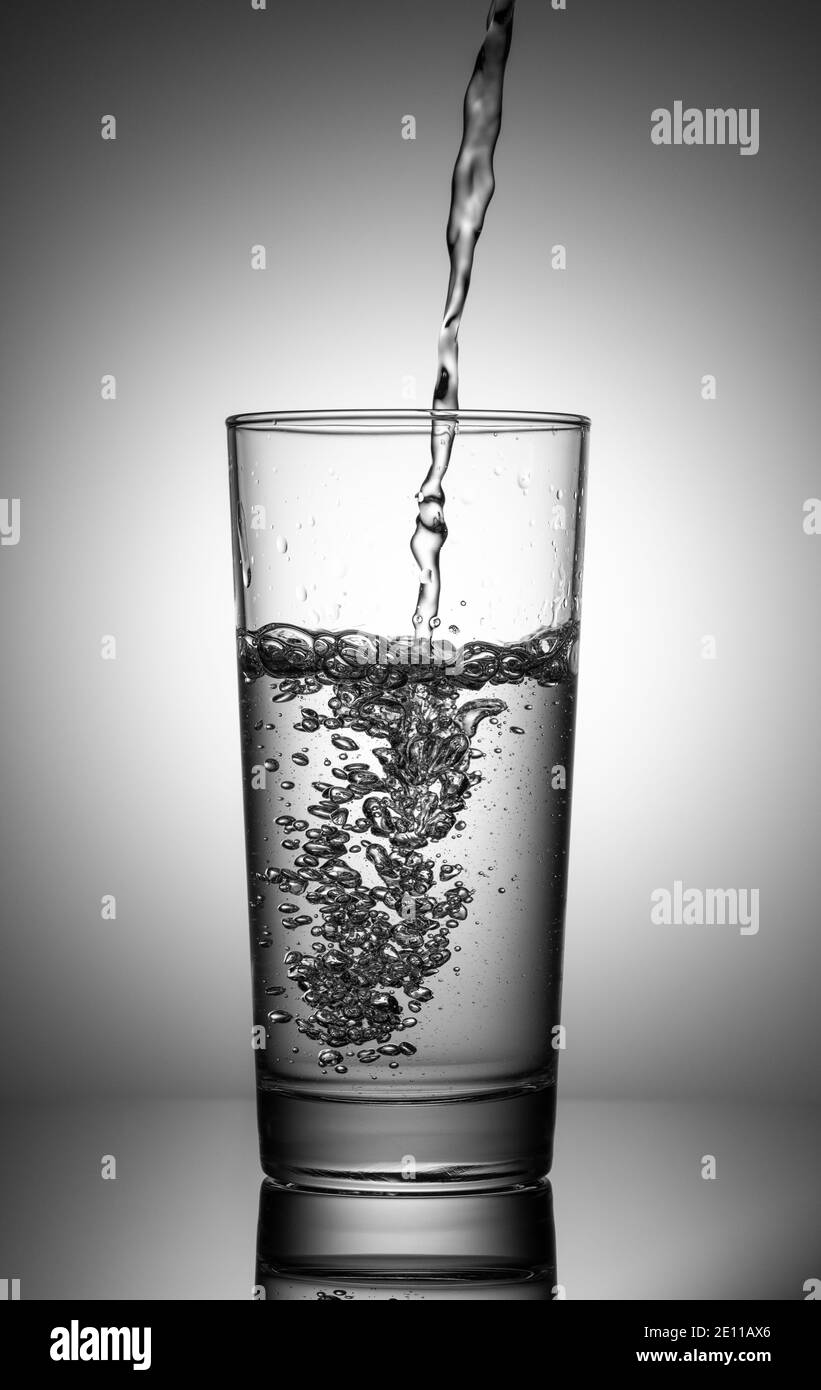Pouring water into a glass against a light background. Dynamic water ...