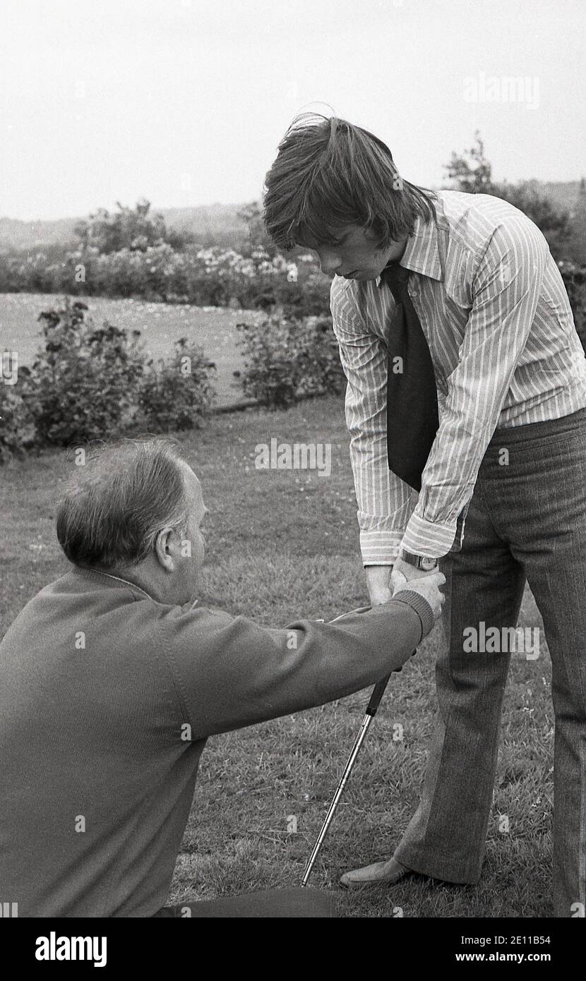 1970s, historical, outside on a grass verge by a putting green, a ...