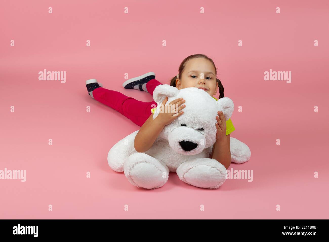 playful contented girl with ponytails and red pants and light green t ...