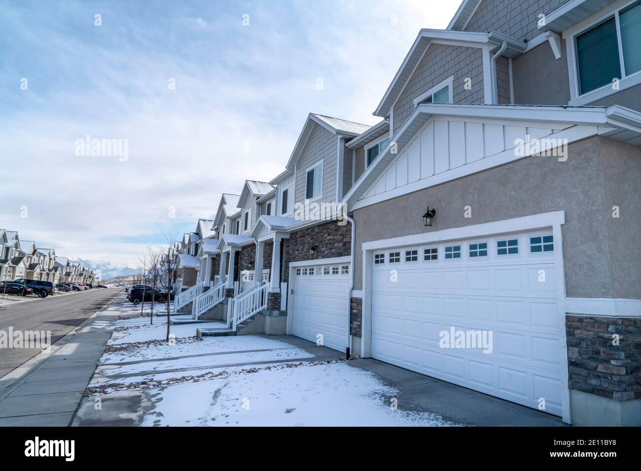 Suburban neighborhood with road along snowy driveways of townhouses in ...