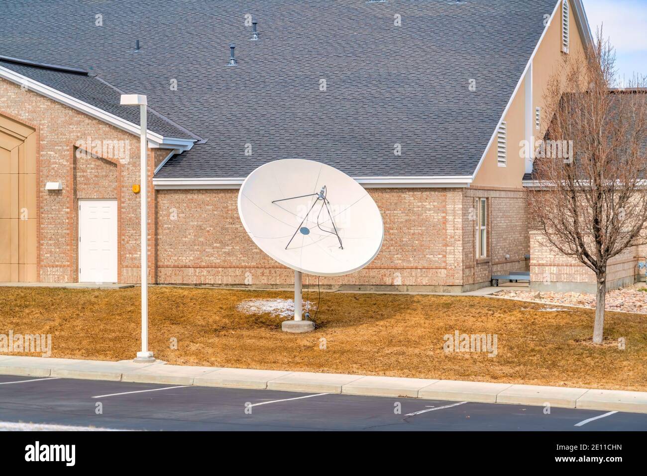 Parabolic satellite dish on grassy lawn in front of building with brick ...