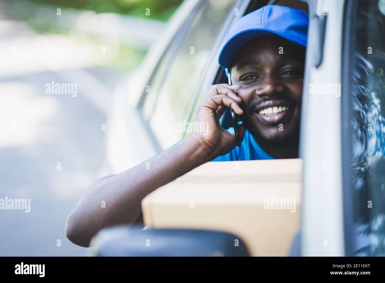 African postal delivery courier man using smart phone and delivering ...