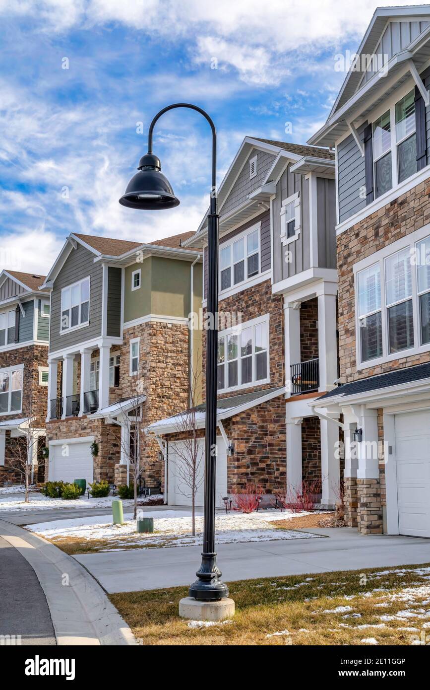 Neighborhood landscape with street lamp post against homes and snowy ...