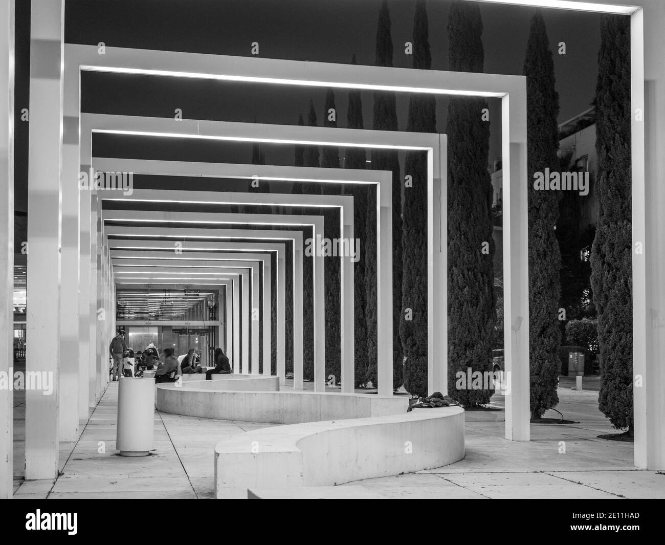 A magical urban crossing with seating is photographed at night in a ...