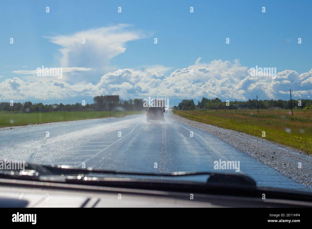 wet road with running vehicles after rain on a summer sunny day ...