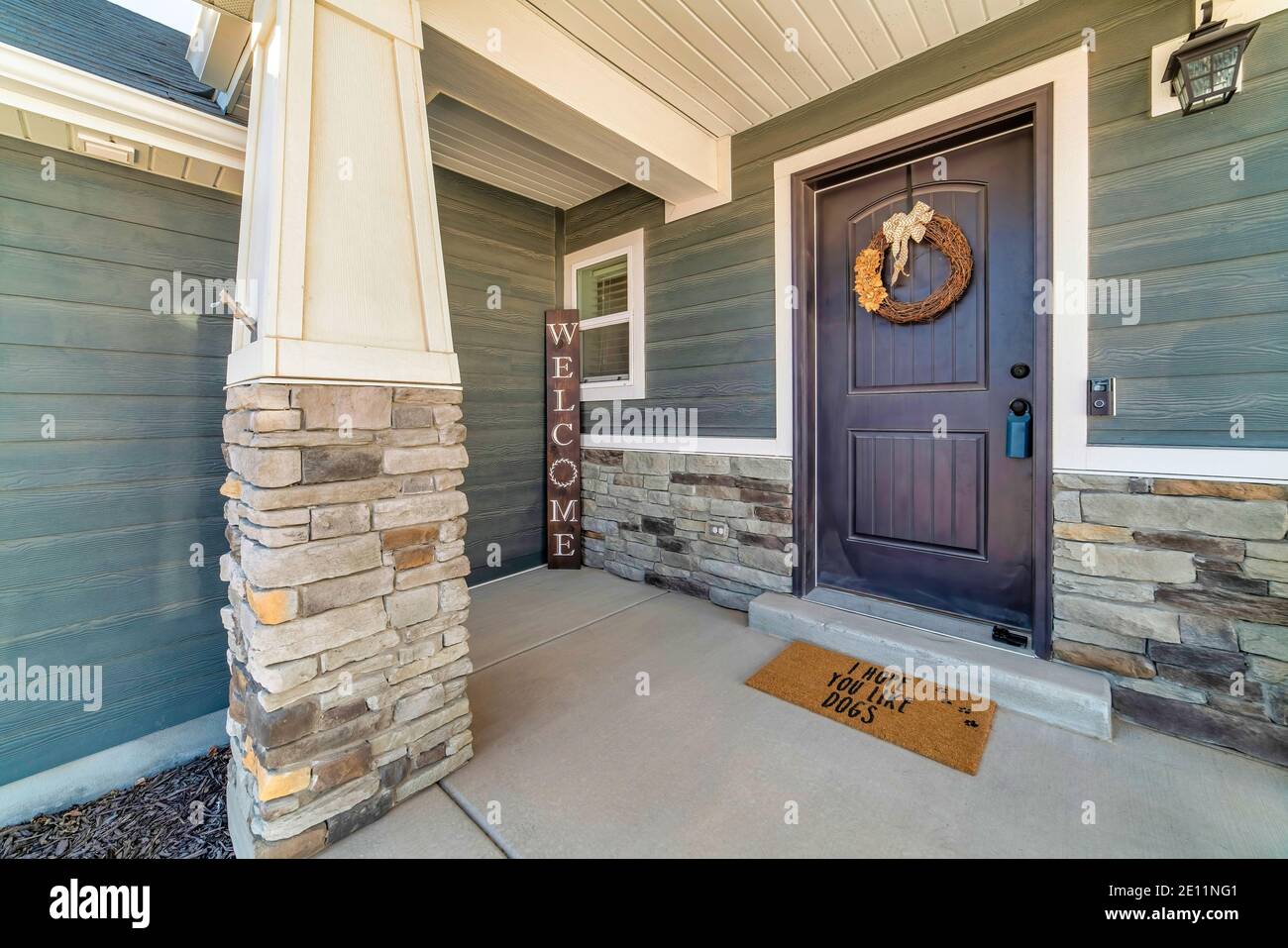 Open porch at home facade with stone wall wood siding and wreath on ...