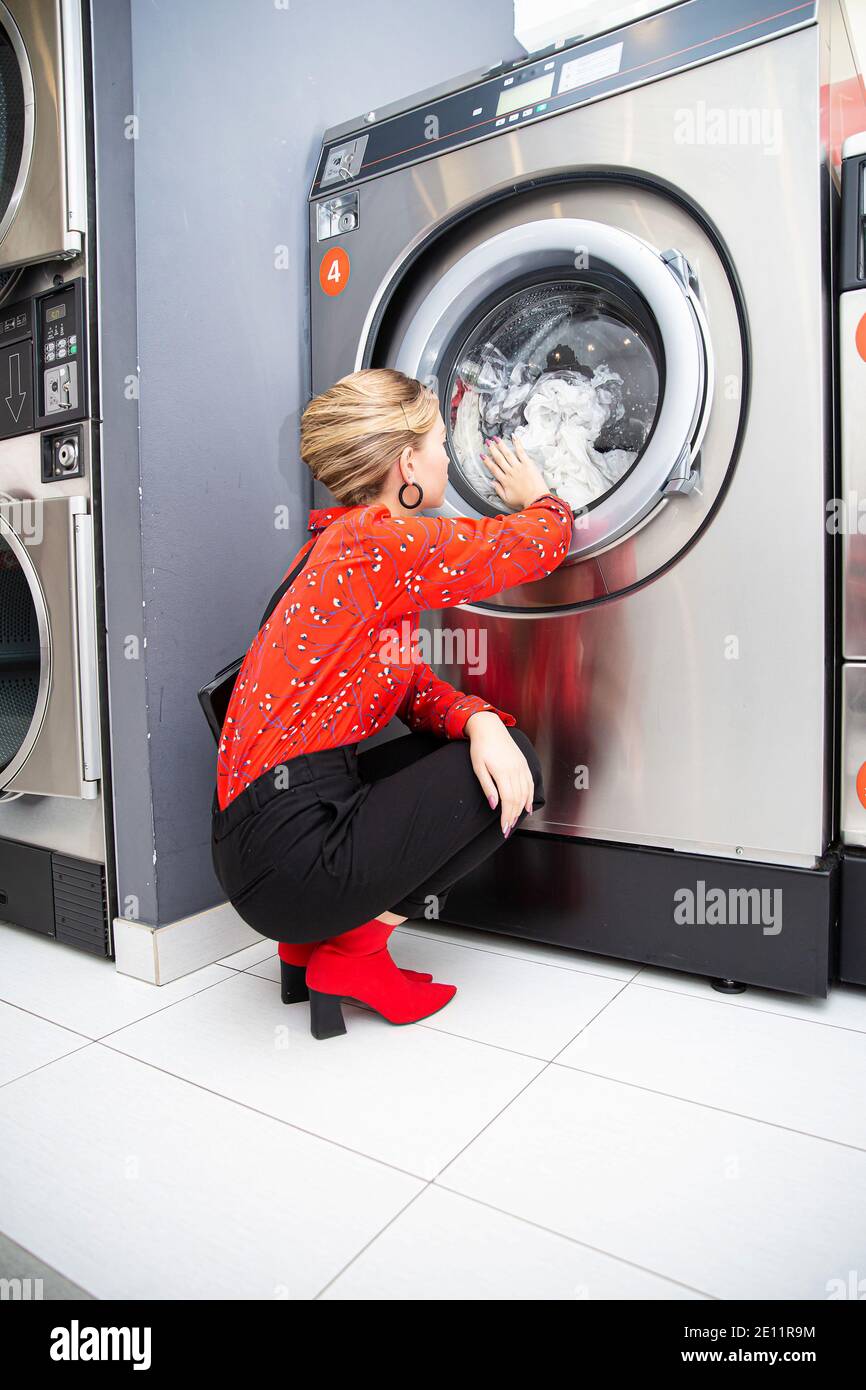 Girl model in red skirt hands behind the head washing machine behind ...