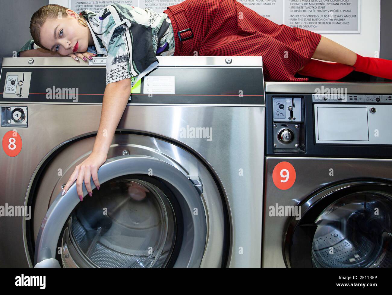 Blond young woman lying on washing machine Stock Photo - Alamy