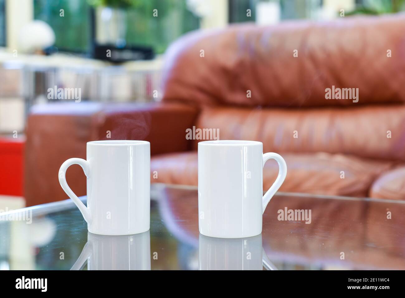 Two cups of tea or coffee together on a coffee table in a light home ...