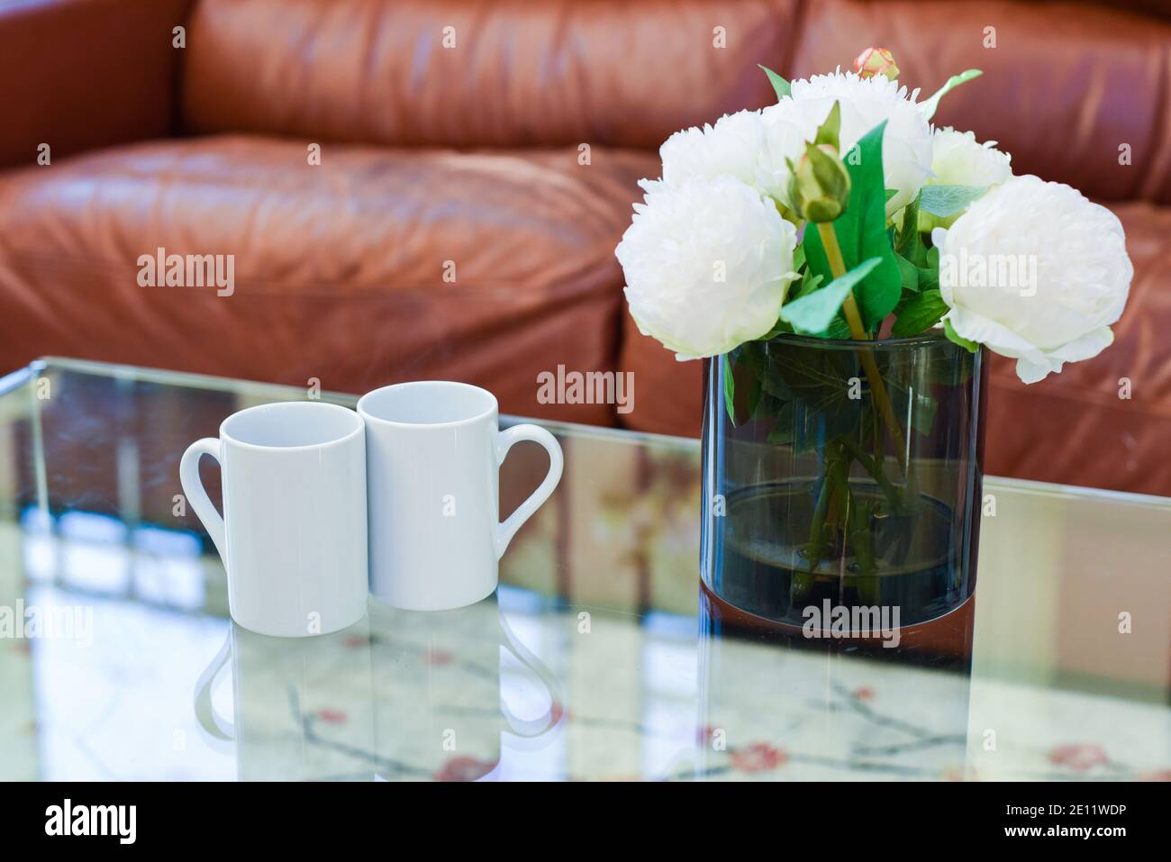 Two cups of tea or coffee together on a coffee table in a light home ...