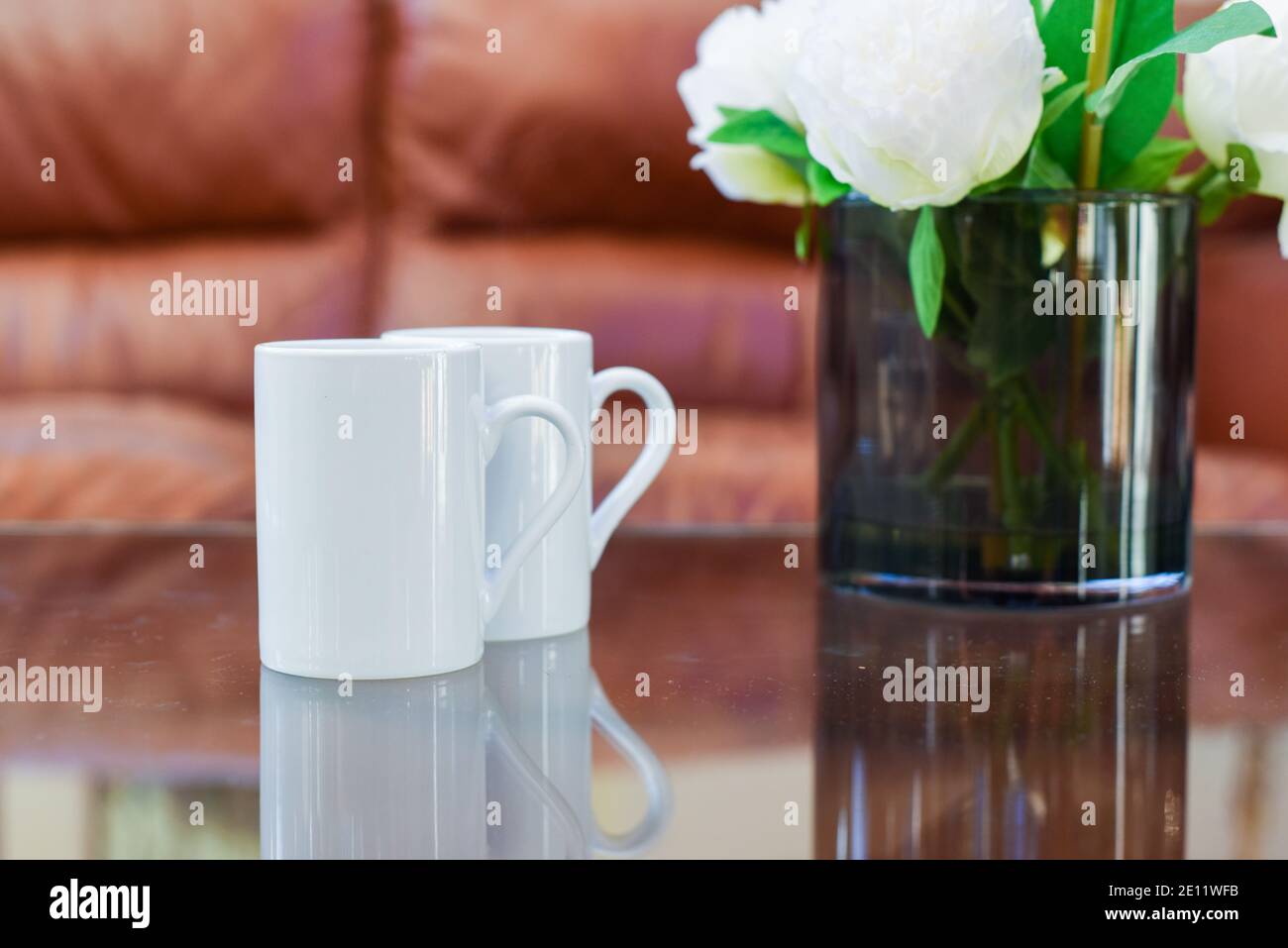 Two cups of tea or coffee together on a coffee table in a light home ...