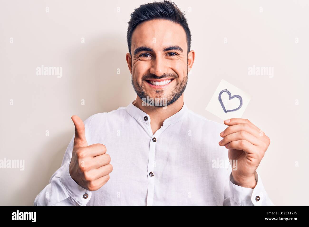 Young handsome romantic man with beard holding reminder with heart ...