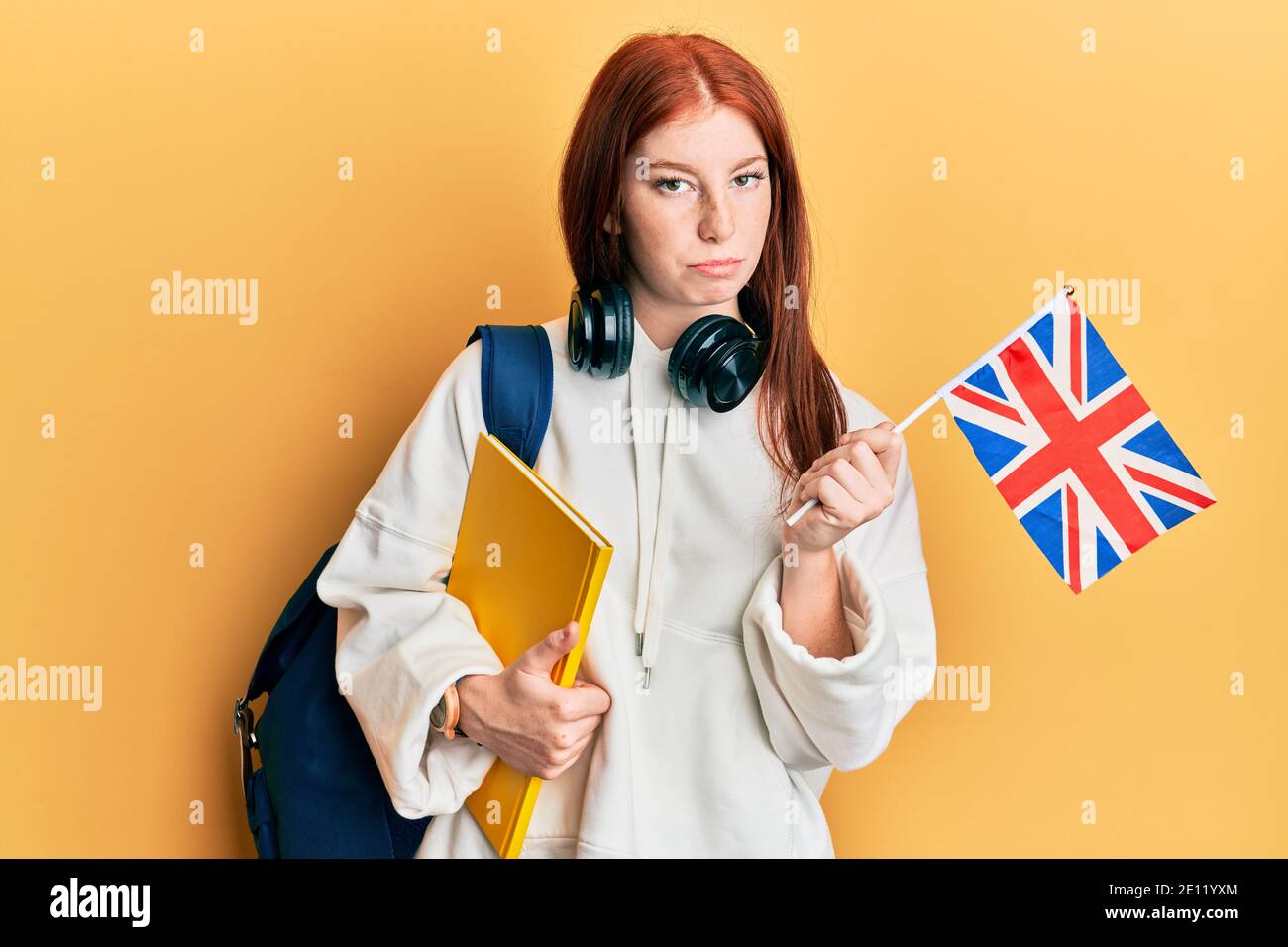 Young red head girl exchange student holding uk flag depressed and ...