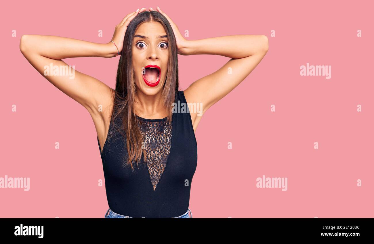 Young hispanic woman wearing casual clothes crazy and scared with hands ...