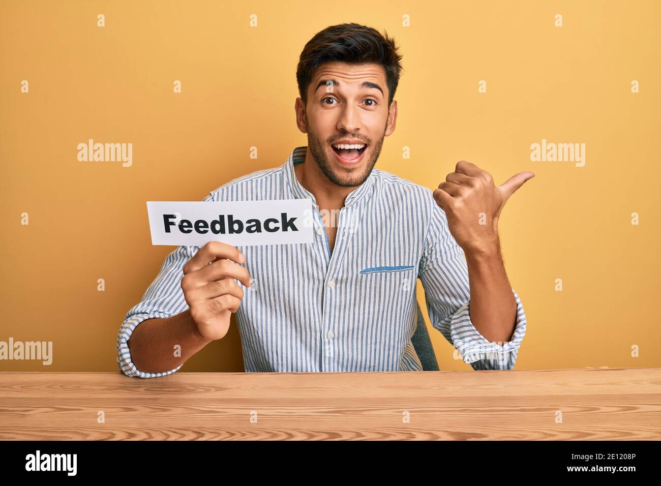 Young handsome man holding feedback paper for customer evaluation ...
