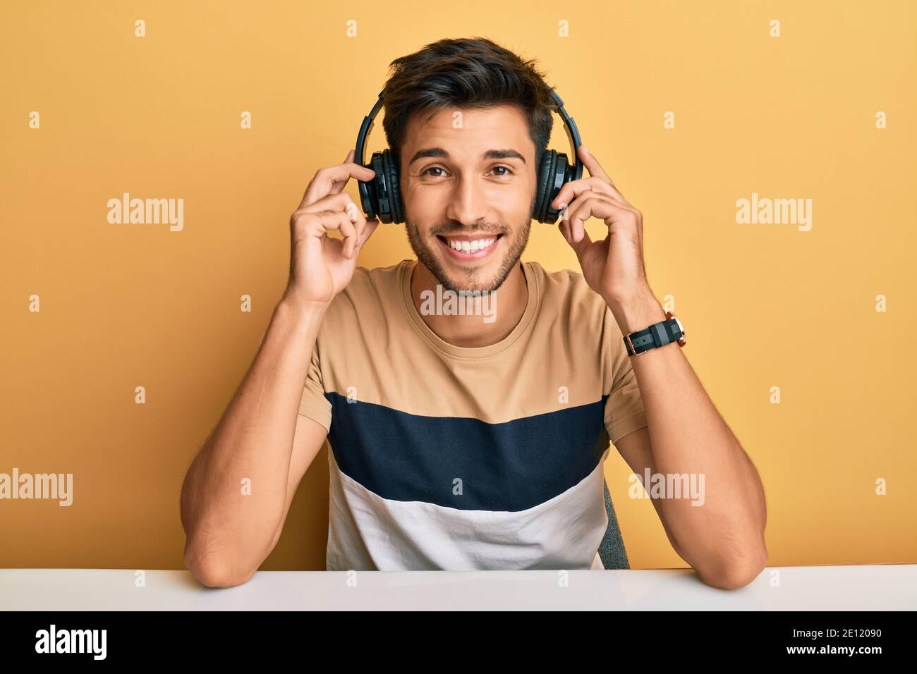 Young handsome man listening to music wearing headphones smiling with a ...