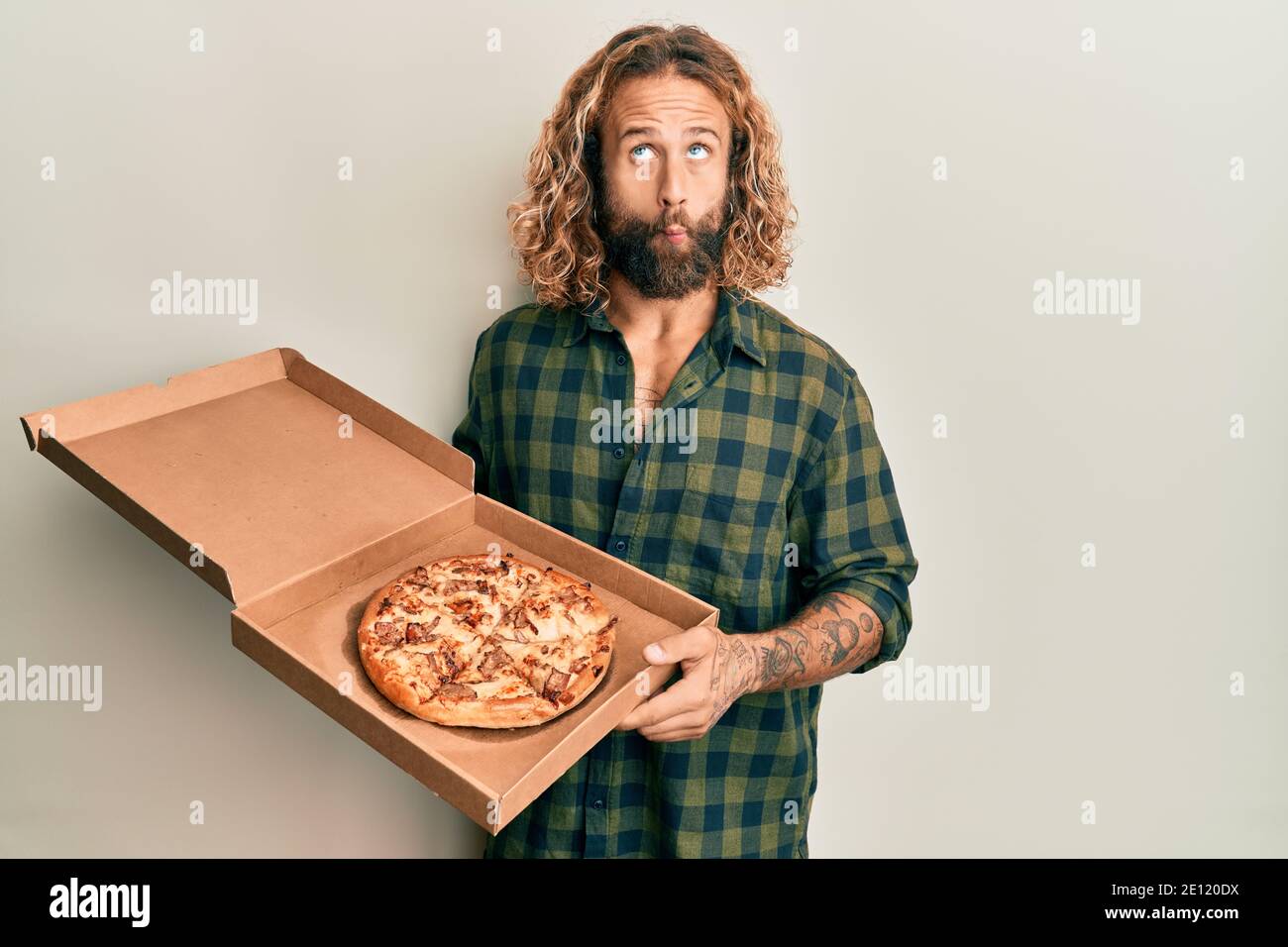 Handsome man with beard and long hair holding italian pizza making fish ...
