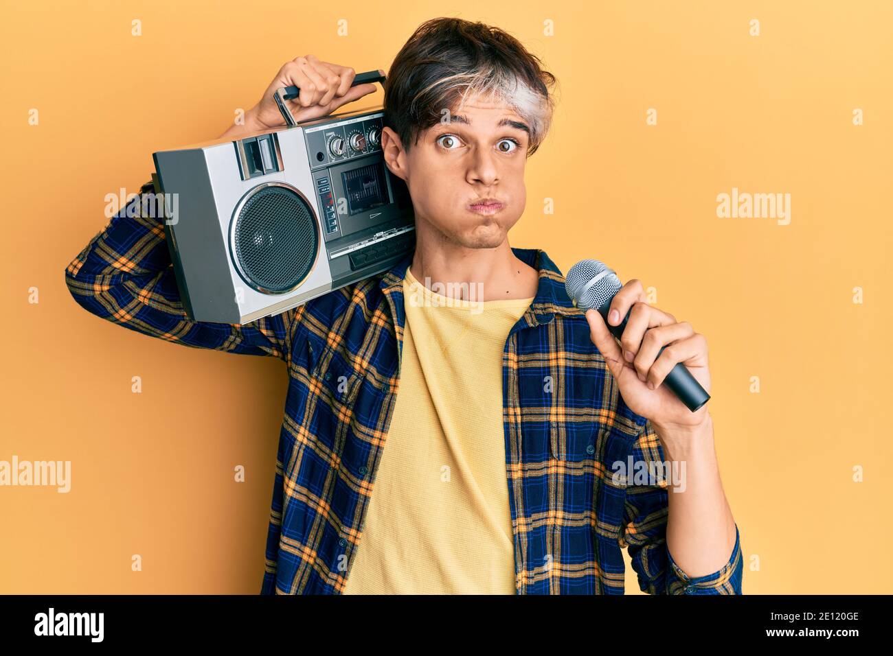 Young hispanic man singing song using microphone and boombox puffing ...