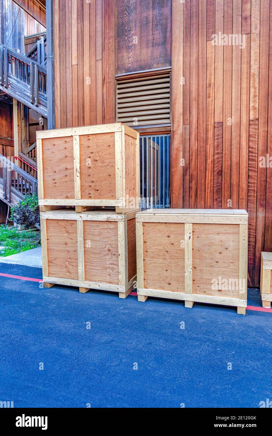 Crate boxes stacked against wooden exterior wall of building with vent ...